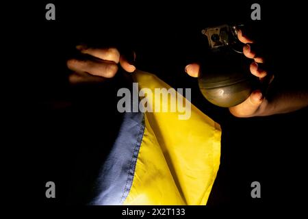 A hand grenade in the hands of a girl in the dark and the flag of ...