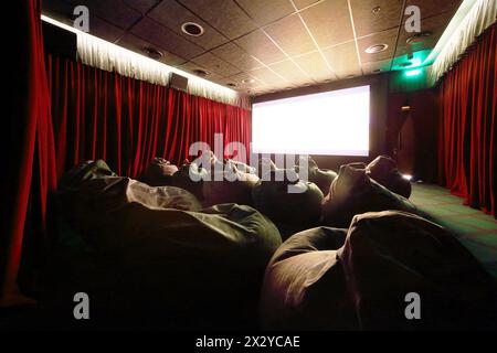 Back of comfortable seats like sacks and white screen in small movie ...