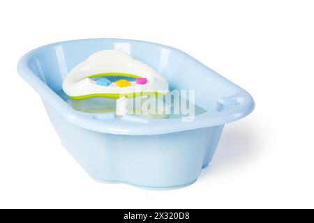 A baby standing in a plastic tub outdoors in a garden, wearing a heart ...