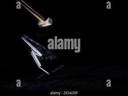 Blow of a big hammer to a computer monitor, isolated on a black ...