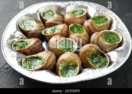 Delicious cooked snails on dark textured table, top view Stock Photo ...