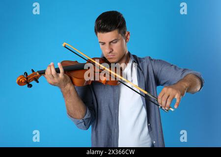 Man playing violin on light blue background Stock Photo - Alamy