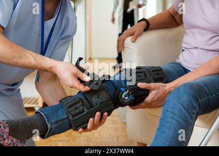 Male physiotherapist helps a woman put on a shin splint after leg ...