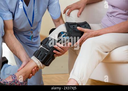 Male physiotherapist helps a woman put on a shin splint after leg ...