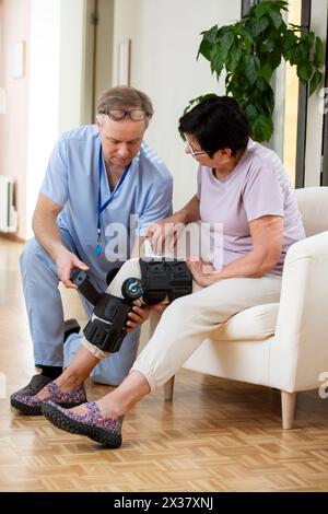 Male physiotherapist helps a woman put on a shin splint after leg ...