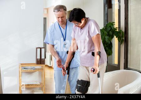 Male physiotherapist helps a woman put on a shin splint after leg ...