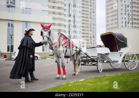 Coachman in cloak stands near couch with horse near residential ...