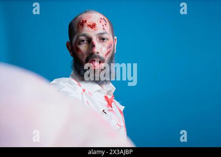 Portrait of brainless zombie isolated over blue studio background ...