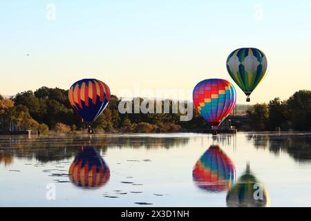 Dawn ascent of vibrant balloons over water Stock Photo - Alamy