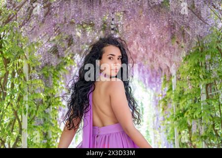 Thoughtful happy mature woman surrounded by chinese wisteria in purple ...