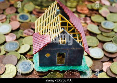 unfinished model house on Euro coins, symbolising the rise in house ...