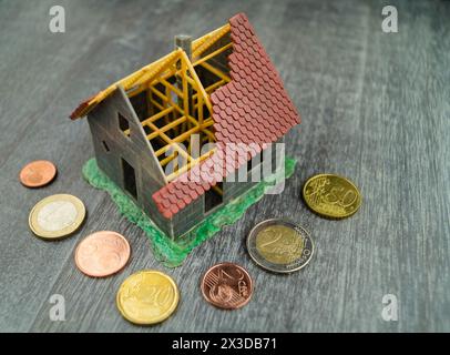 unfinished model house and pile of money, symbolising the rise in house ...