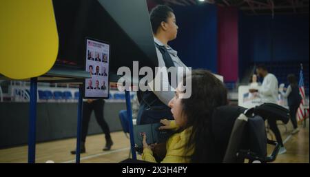 Polling officer consults woman with physical disability. Female US ...