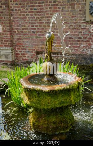 Old moss-covered fountain with a bronze sculpture in a serene garden ...