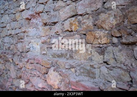 Gray structural stone wall of the ancient building consists of old dark ...