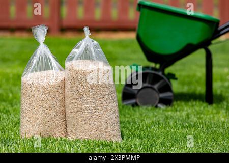 Bags of lawn fertilizer and herbicide in yard with healthy grass. Lawn ...