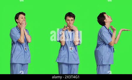 Flirty cute nurse blowing air kisses against greenscreen backdrop ...