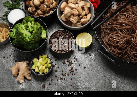 Wok with noodles, chicken and other products on grey table, above view ...