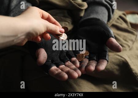 Woman giving coins to poor homeless man with bowl of donations and help ...
