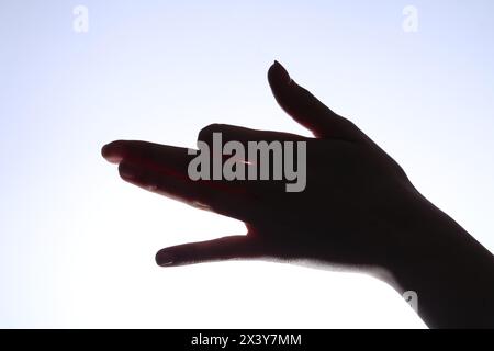 Shadow puppet. Woman making hand gesture like snail on light background ...