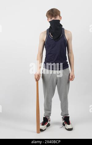 A Teenage Male Gang Member in a mask holding a baseball bat sideways ...