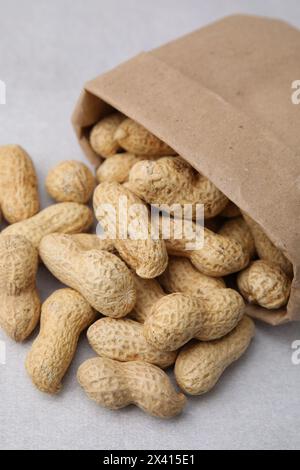 Paper bag with fresh unpeeled peanuts on grey table against blurred ...