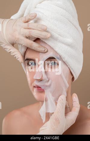 Beautiful woman with a cloth moisturizing mask for the face. Facial and ...