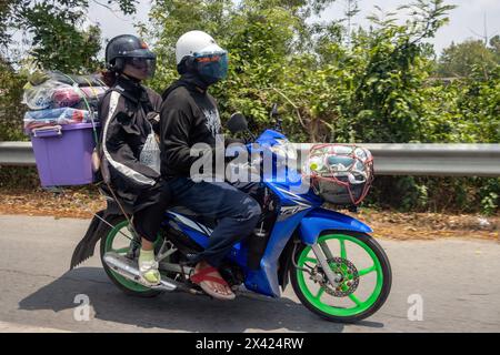THAILAND, APR 15 2024, A couple is riding a loaded motorcycle along the ...