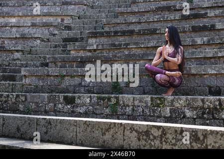 Content female in sportswear balancing in Padangusthasana with Namaste ...
