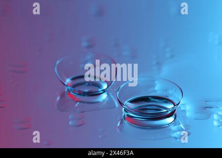Pair of contact lenses on mirror surface, toned in blue. Space for text ...