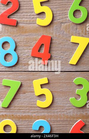 A flat lay of colorful wooden numbers on a yellow surface - space for ...
