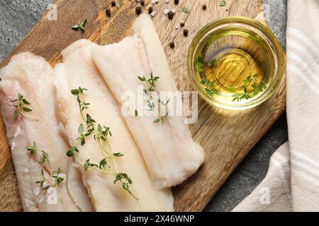 Raw cod fish, microgreens, oil and spices on grey textured table, top ...