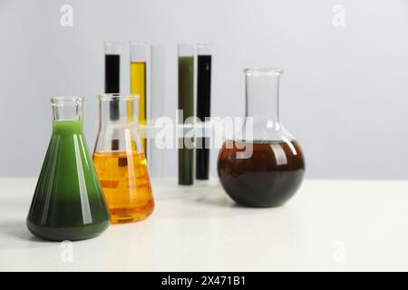 Laboratory glassware with different types of oil on white table, space ...