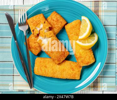 crispy fried battered alaskan pollock fillet on blue dish with lemon ...