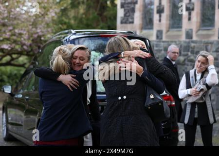 Mourners embrace each other as the hearse, carrying the coffin of ...