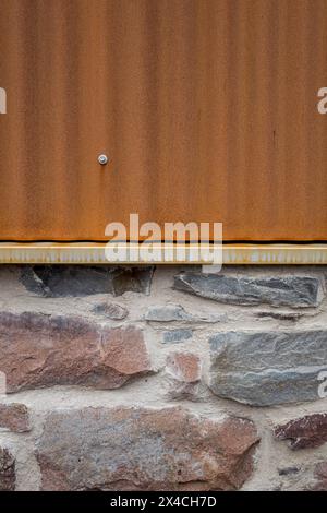 Thin layer of rust on a corrugated steel sheet and local stone wall and ...