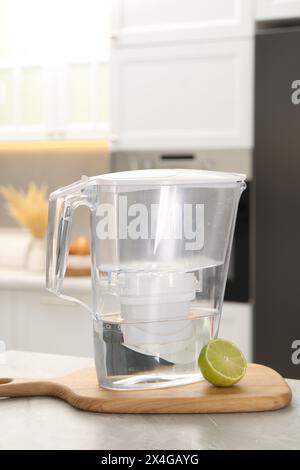 Water filter jug and lime on light table in kitchen. Space for text ...