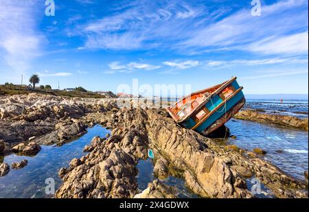 Shipwrecked diamond mining vessel on rocky shoreline in small West ...