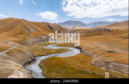 River Kol Suu winds through a mountain valley with hills of yellow ...