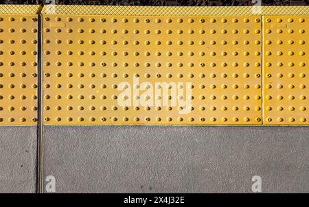 Yellow warning tile bumps in front of train tracks Stock Photo - Alamy