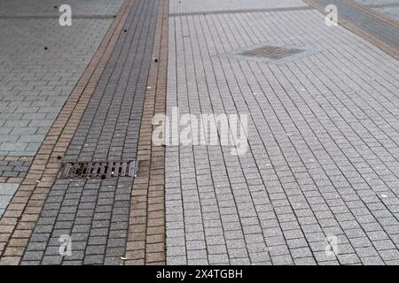 Deserted paved pedestrian zone with gully cover Stock Photo - Alamy