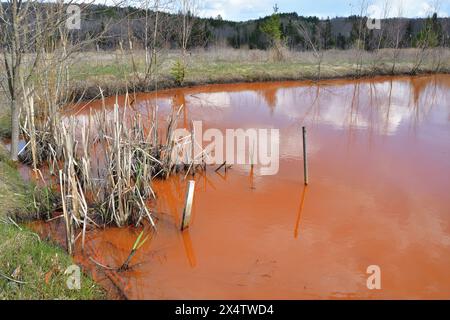 Sedimentation basin on old copper mining site. Pond with orange water ...