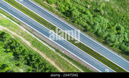 An aerial view of an asphalt highway cutting through a dense forest of ...