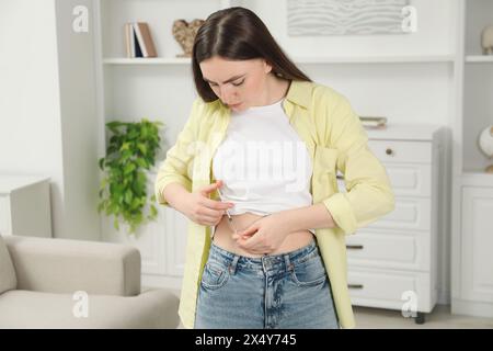 Diabetes. Woman making insulin injection into her leg on bed in room ...