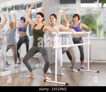 Girl doing plie exercise in class with teens in ballet studio under ...