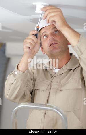 happy builder fitting a light bulb Stock Photo - Alamy