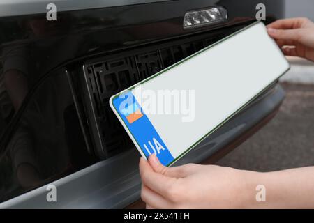 Woman installing vehicle registration plate outdoors, closeup Stock ...