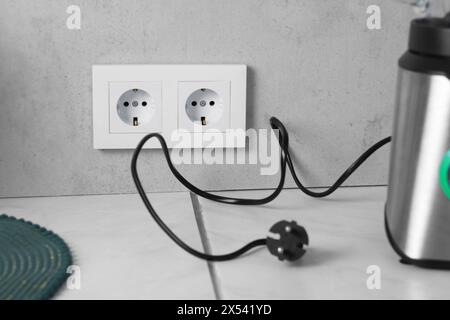 Power sockets and blender on white table Stock Photo - Alamy