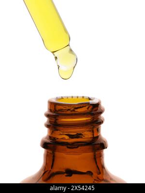 Dripping tincture from pipette into bottle on white background, closeup ...