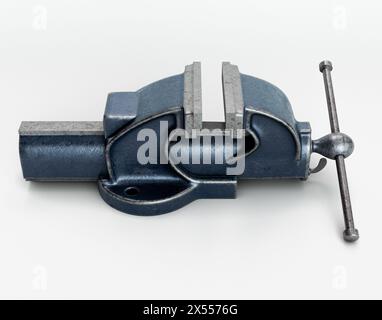 An industrial cast iron bench vice grip mounted on a metal workbench ...